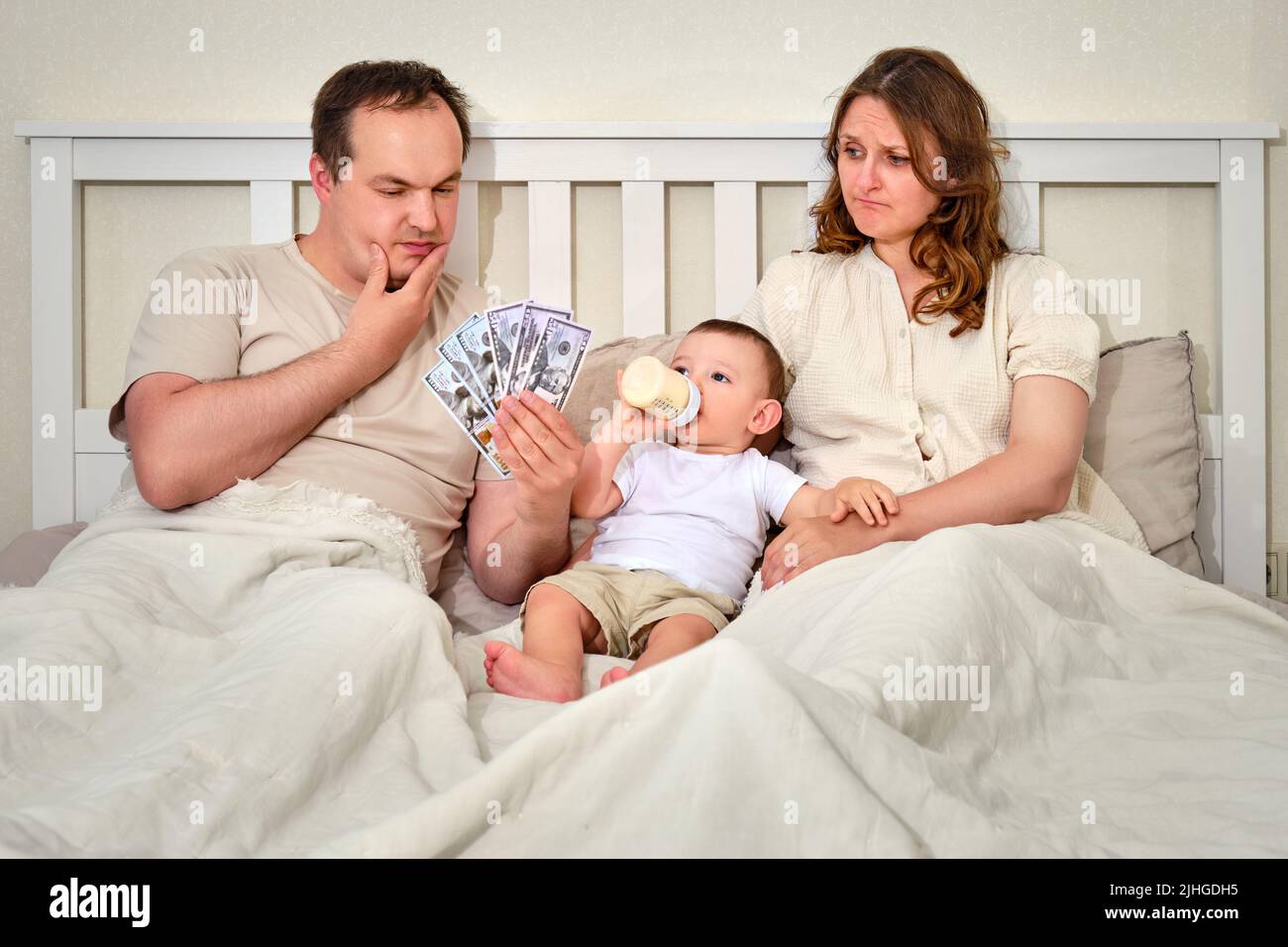 Mother, fatherb and baby boy with dollars money for upbringing ...