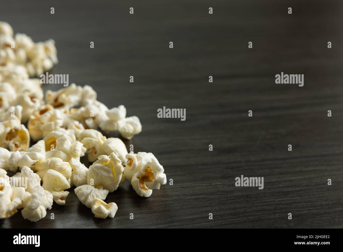 Border of freshly popped popcorn on a dark wood background with copy ...