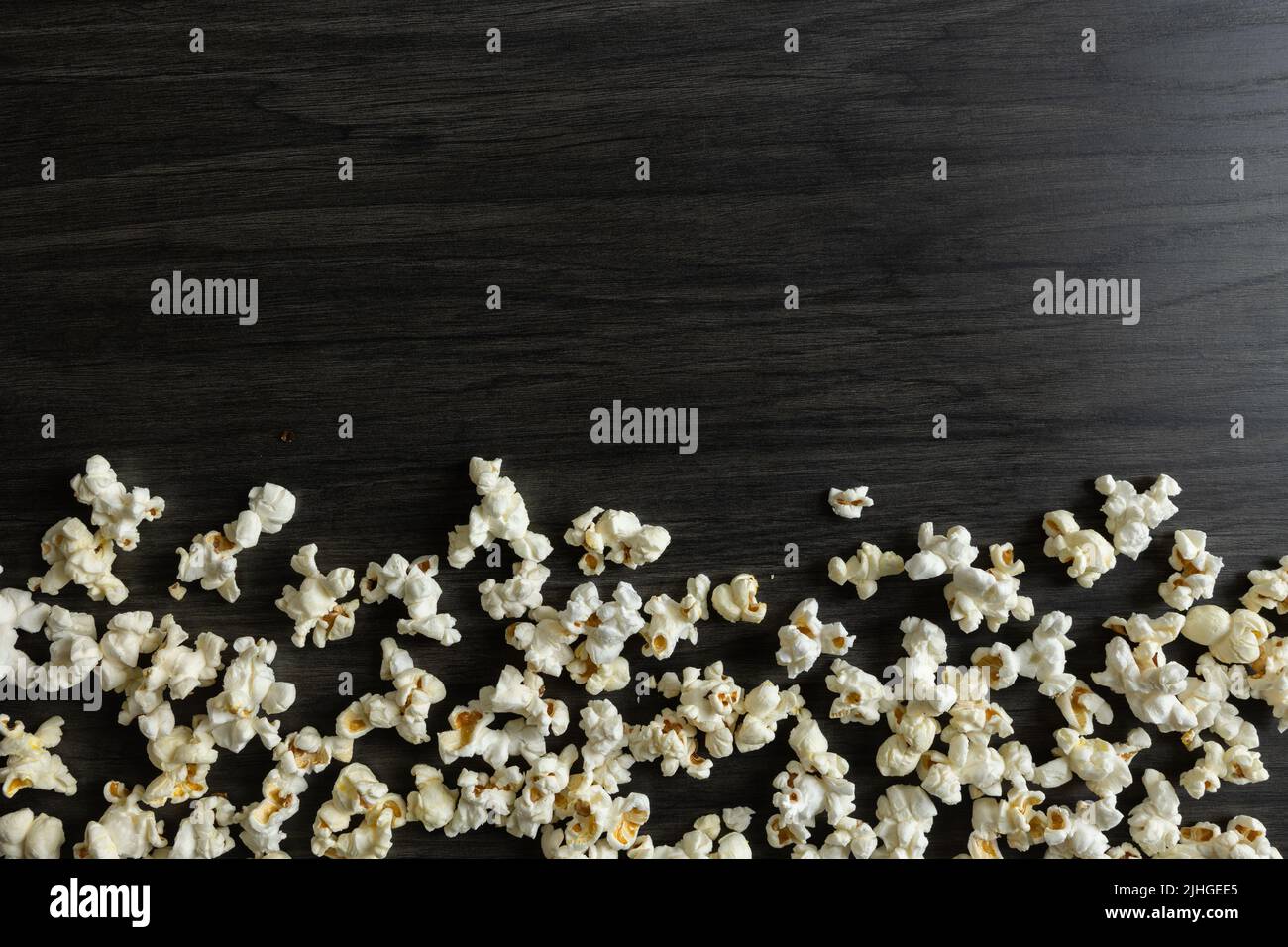 Border of freshly popped popcorn on a dark wood background with copy ...