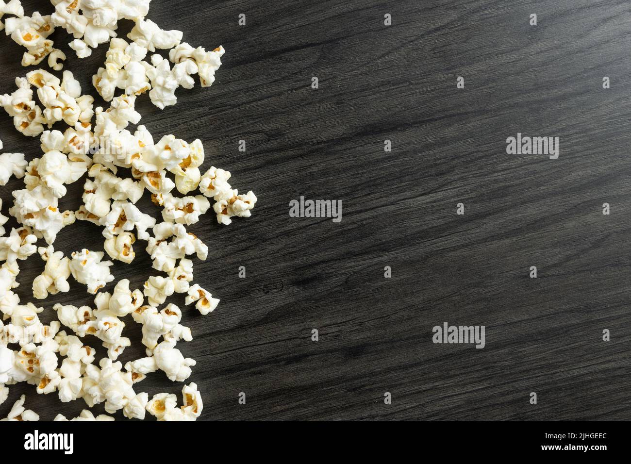 Border of freshly popped popcorn on a dark wood background with copy ...