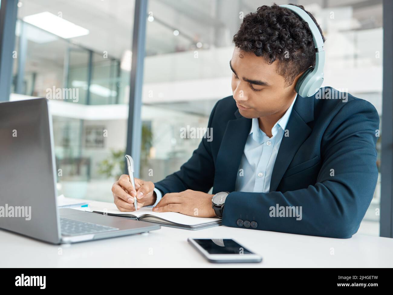 Young serious mixed race businessman wearing headphones listening to ...