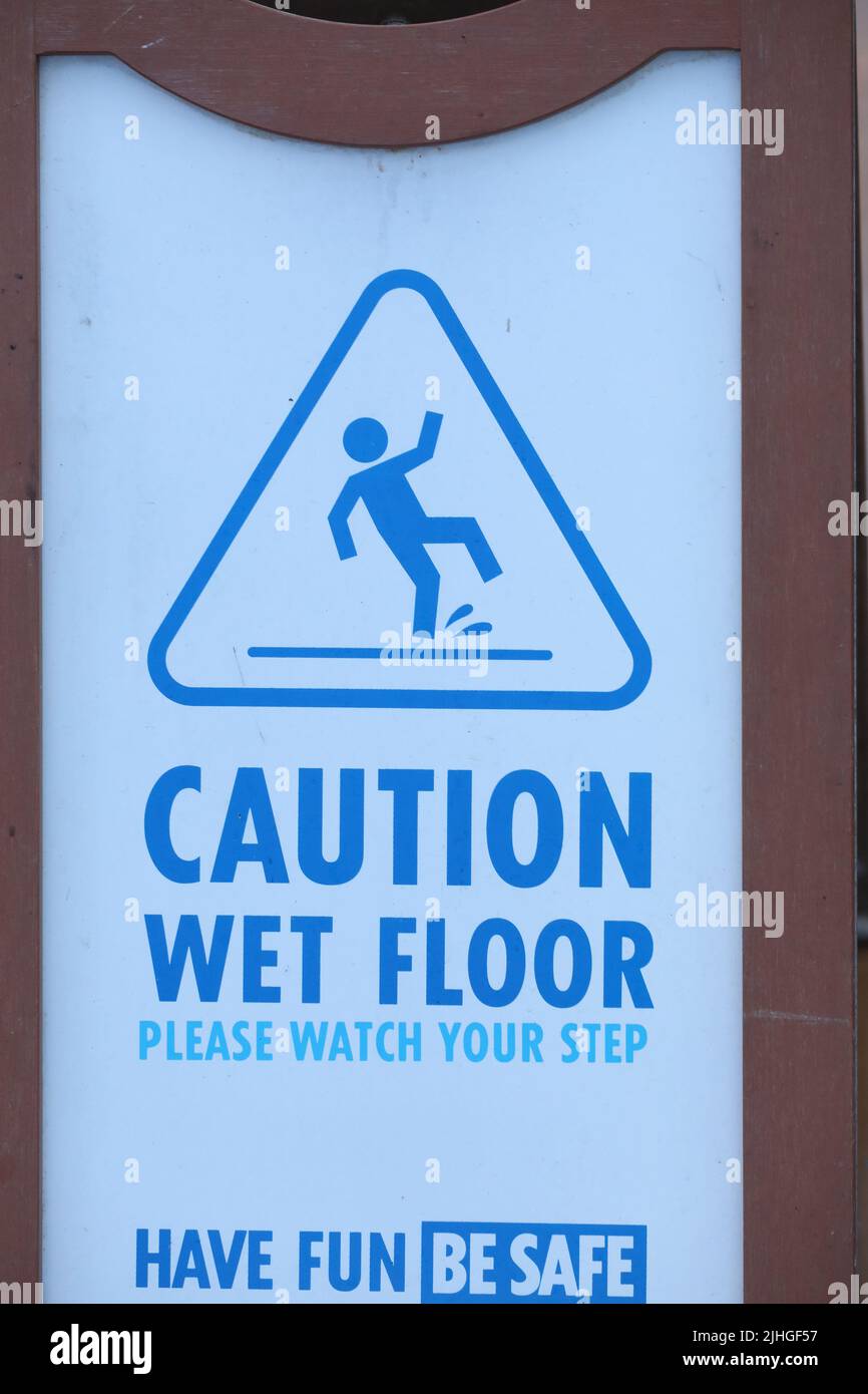Wet floor caution sign on walkway near the building after raining ...