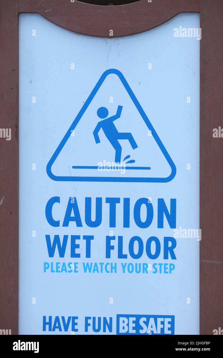 Wet floor caution sign on walkway near the building after raining ...