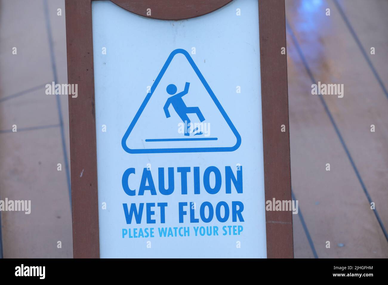 Wet floor caution sign on walkway near the building after raining ...