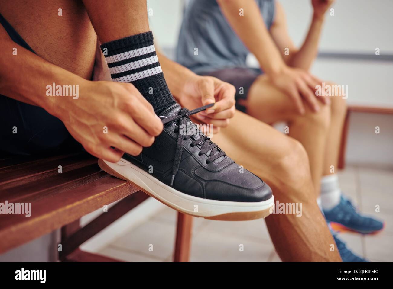 Squash player tying his shoe lace. Hands of a fit athlete getting ready ...