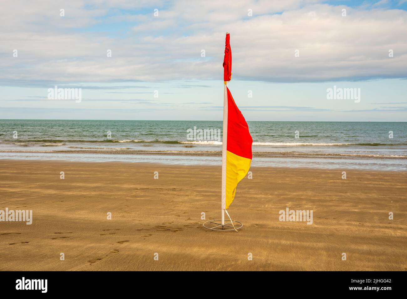 red and yellow warning flag isolated on a beach Stock Photo - Alamy