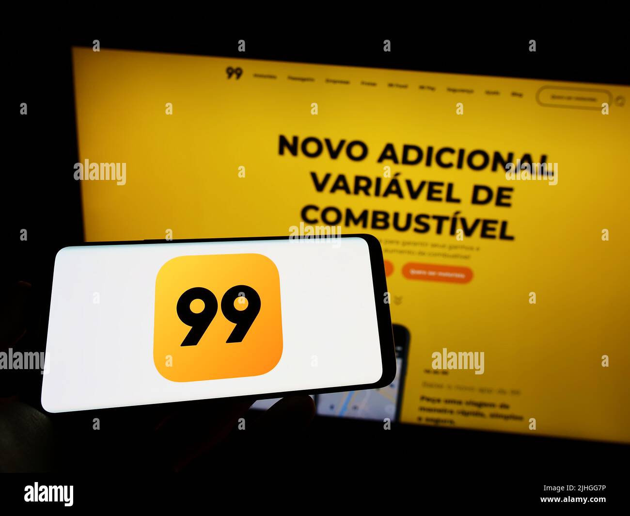Person holding mobile phone with logo of Brazilian company 99 ...