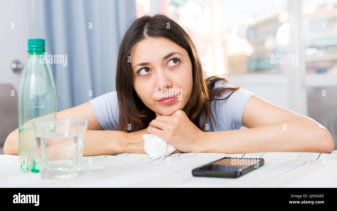 Sad young woman thinking at table with glass of water indoors Stock ...