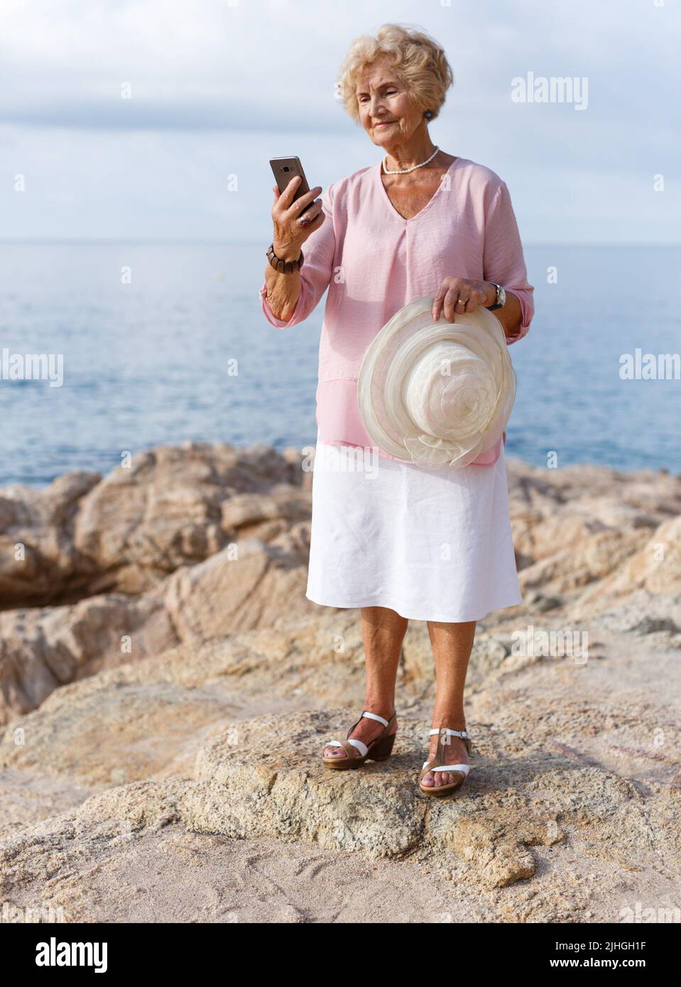 Elderly woman using phone at seaside Stock Photo - Alamy