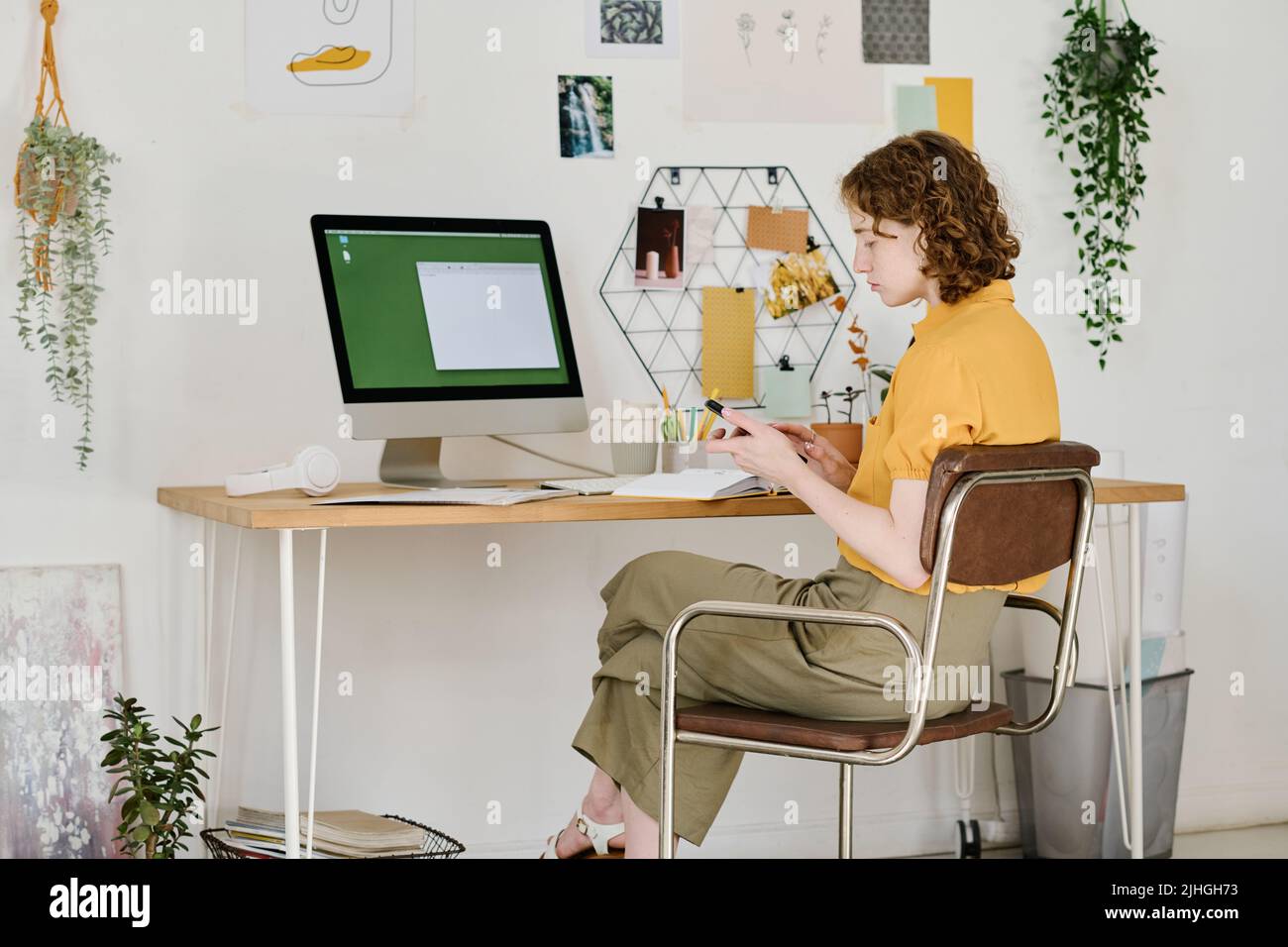 Young serious businesswoman scrolling in mobile phone while sitting in ...