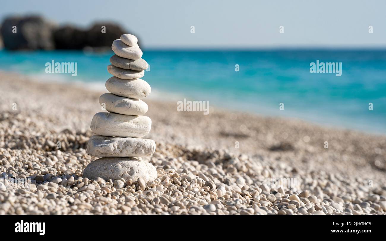 Stacked stones on a beautiful white pebble beach in the Mediterranean ...