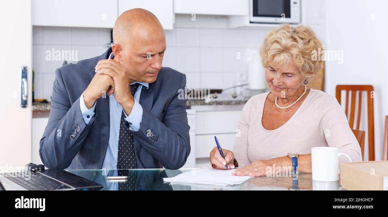 Agent helping to elderly woman Stock Photo - Alamy