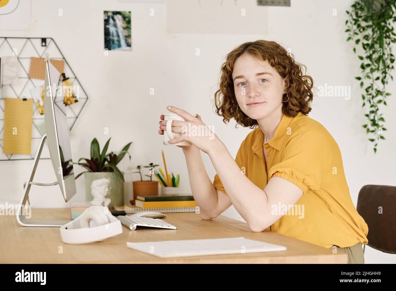 Happy young female freelancer or home office worker having tea or ...