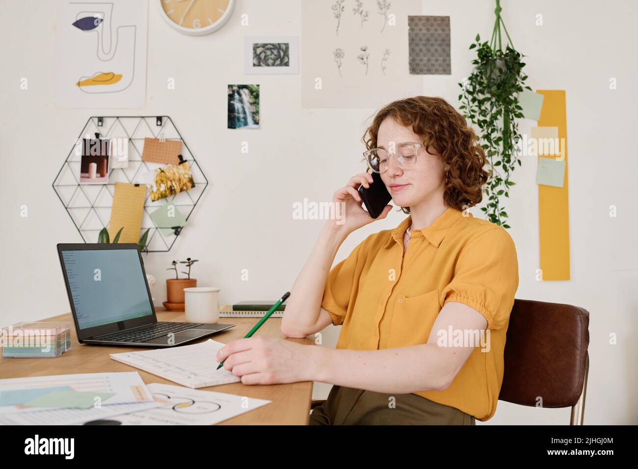 Young woman with smartphone by ear organizing work and calling clients ...