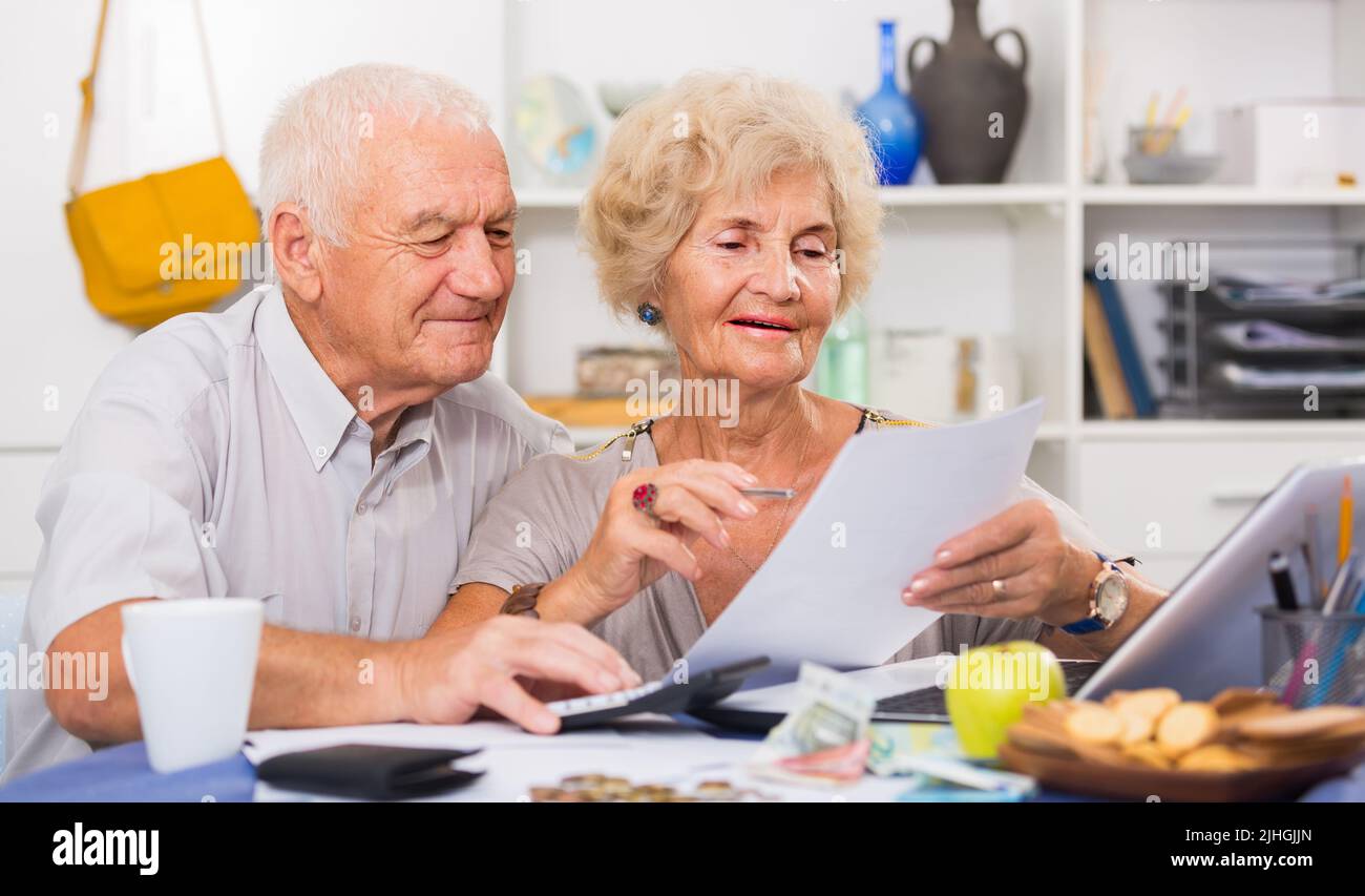 Happy senior spouses with bills and laptop Stock Photo - Alamy