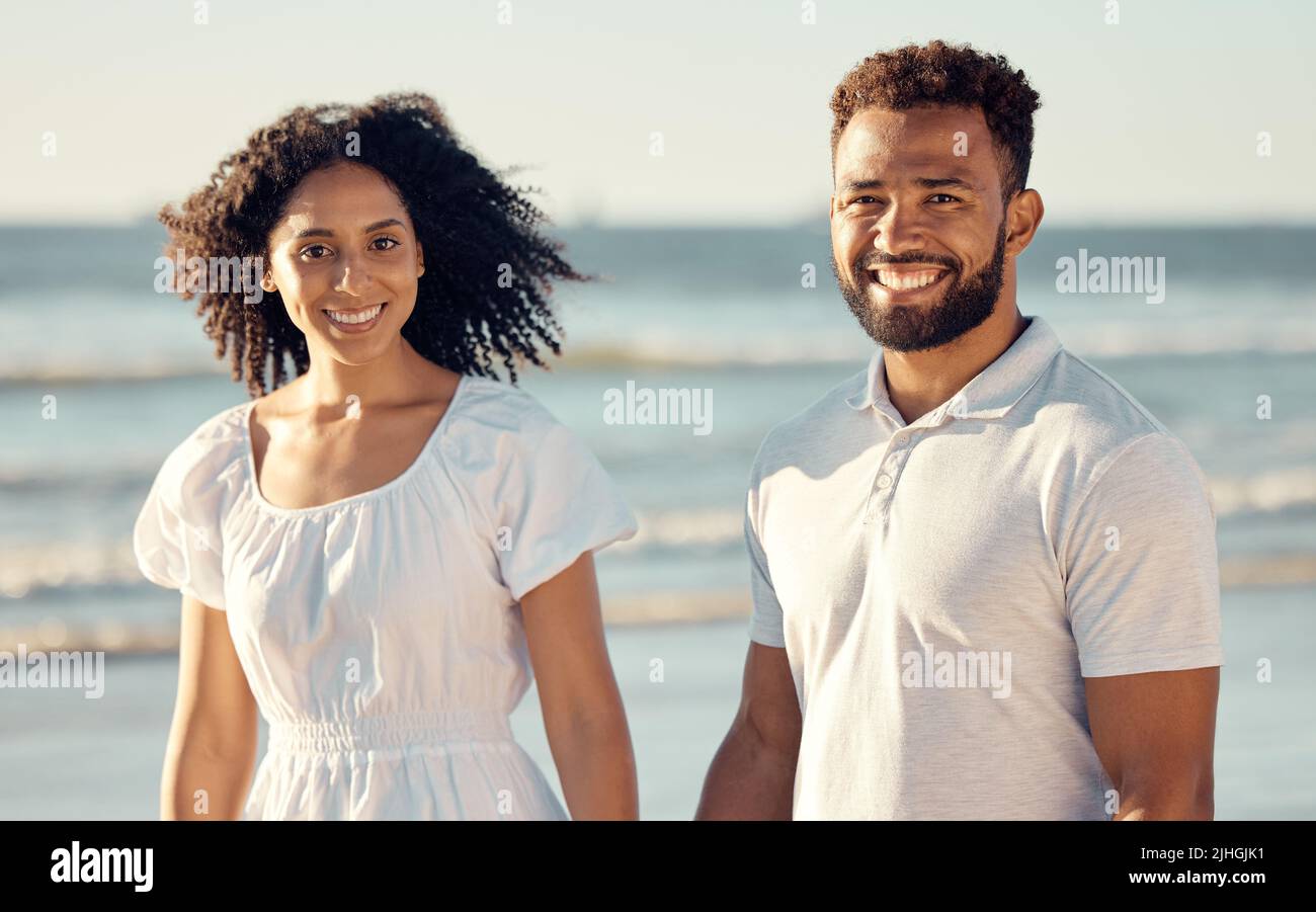 Happy mixed race young couple holding hands while walking on the beach ...