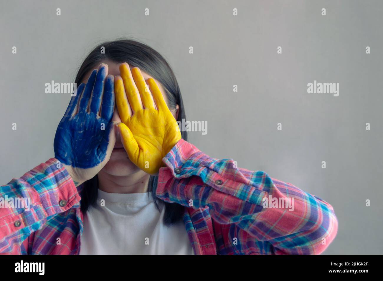 Young woman covered her face hand painted of blue yellow ukrainian flag ...