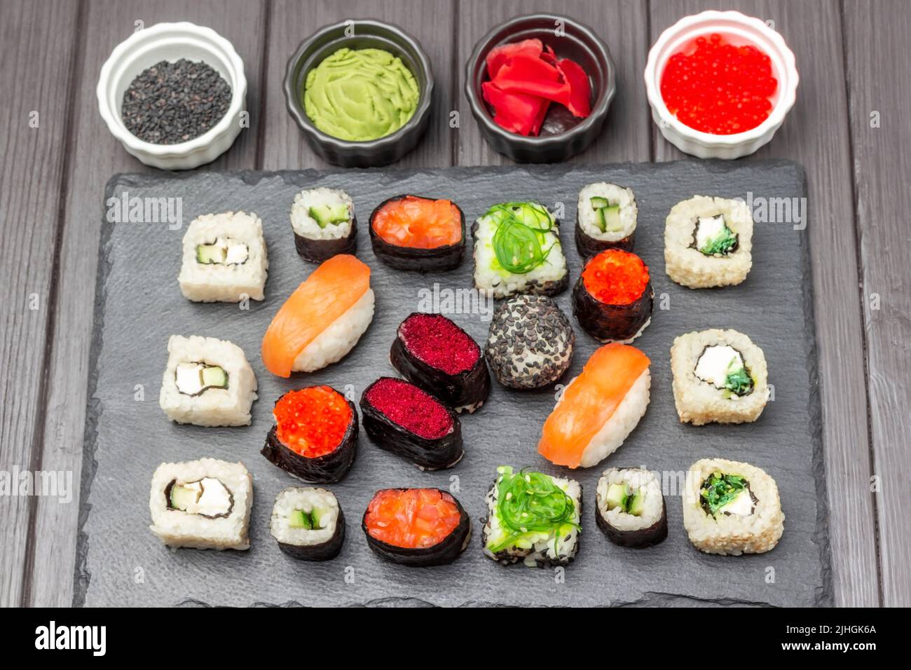 Sushi set on black stone board. Wasabi, pink ginger, black sesame in ...