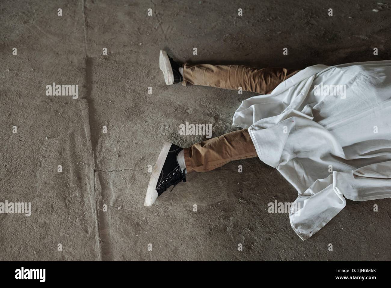 Above view of legs of young man shot dead lying on asphalt in parking ...