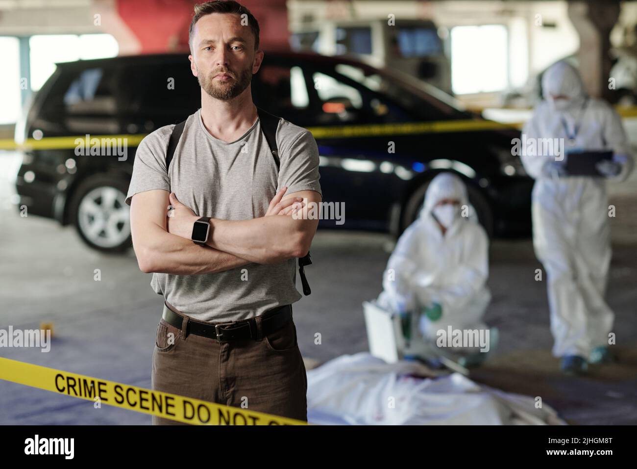 Young serious policeman with his arms crossed on chest looking at ...