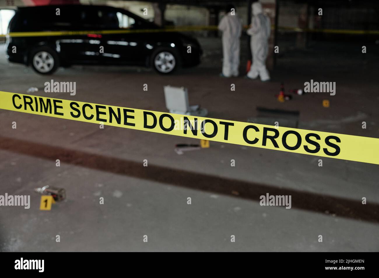 Yellow tape surrounding crime scene in parking area with two experts in ...