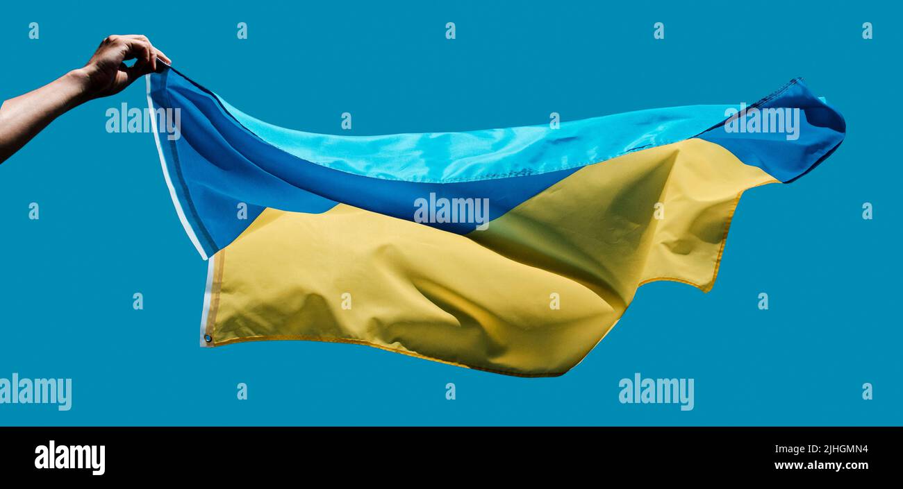 closeup of a man flying the ukrainian flag on the sky, in a panoramic ...