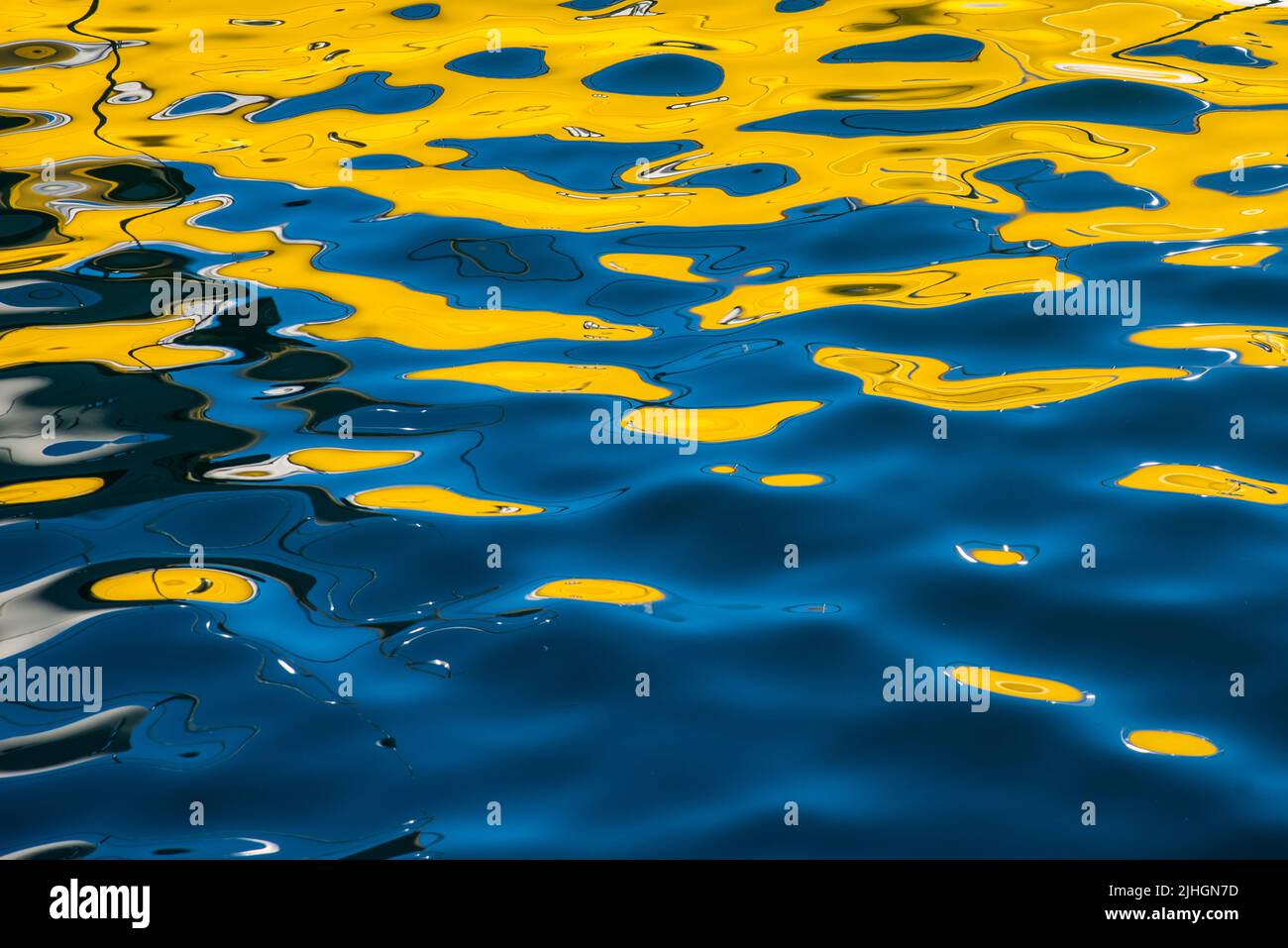 Yellow reflections rippling in blue water Stock Photo - Alamy