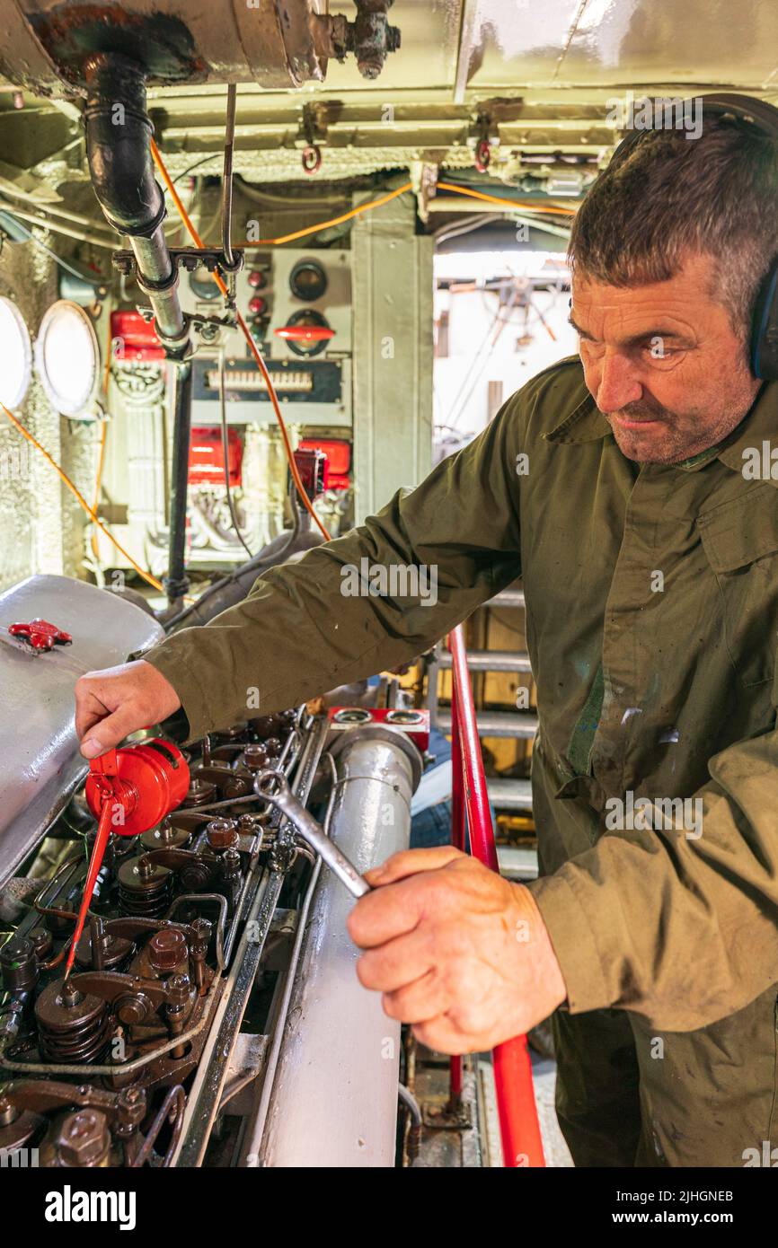 Man, engineer, oiling a large diesel engine in the engine room of the ...