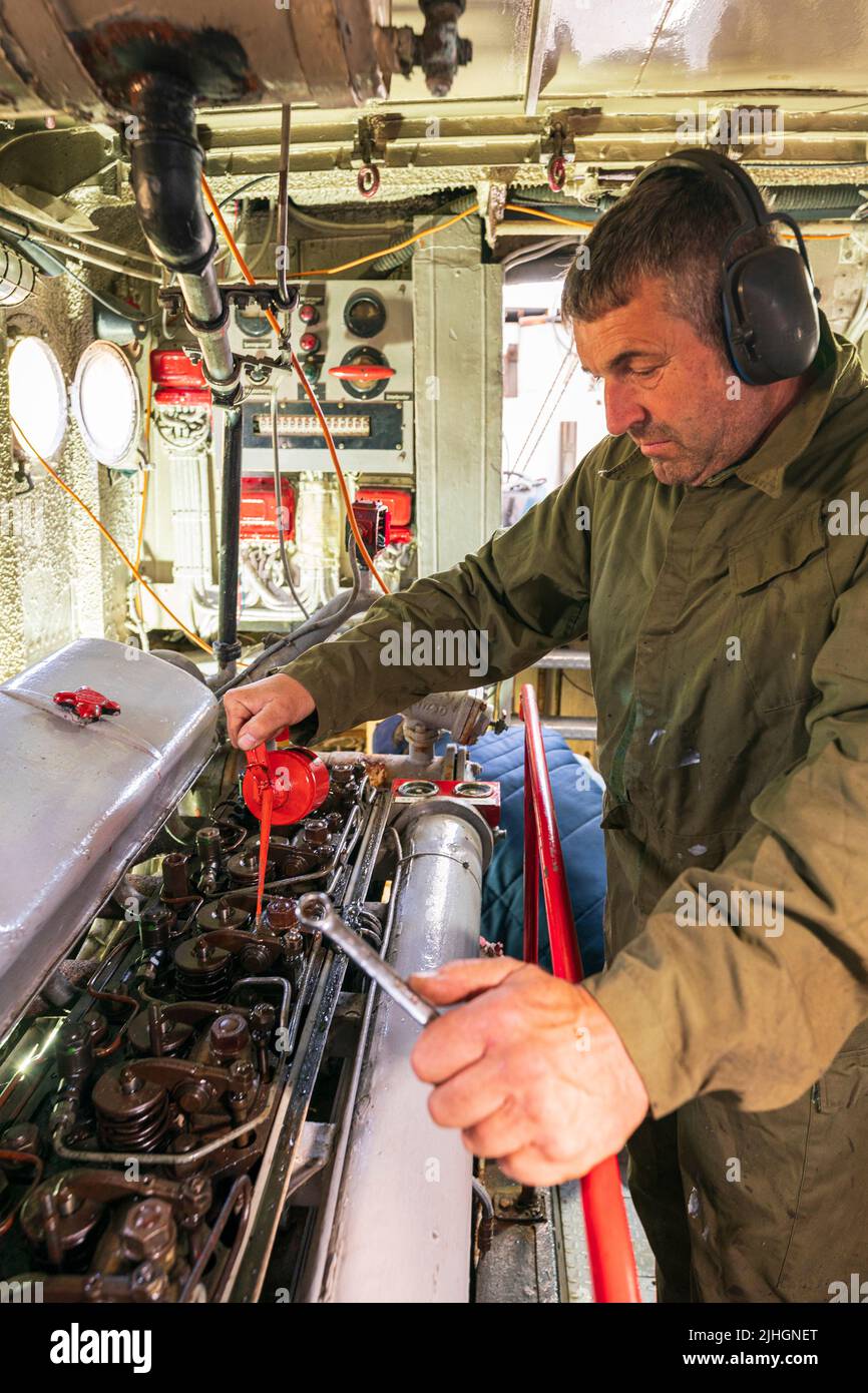 Man, engineer, oiling a large diesel engine in the engine room of the ...