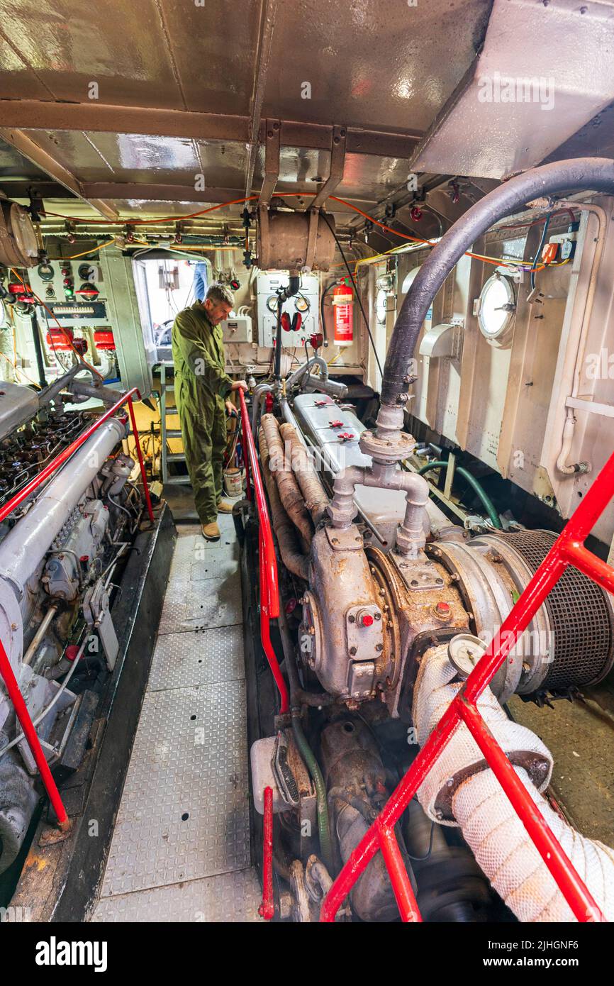 Man, engineer, standing between two large diesel engines, one with open ...