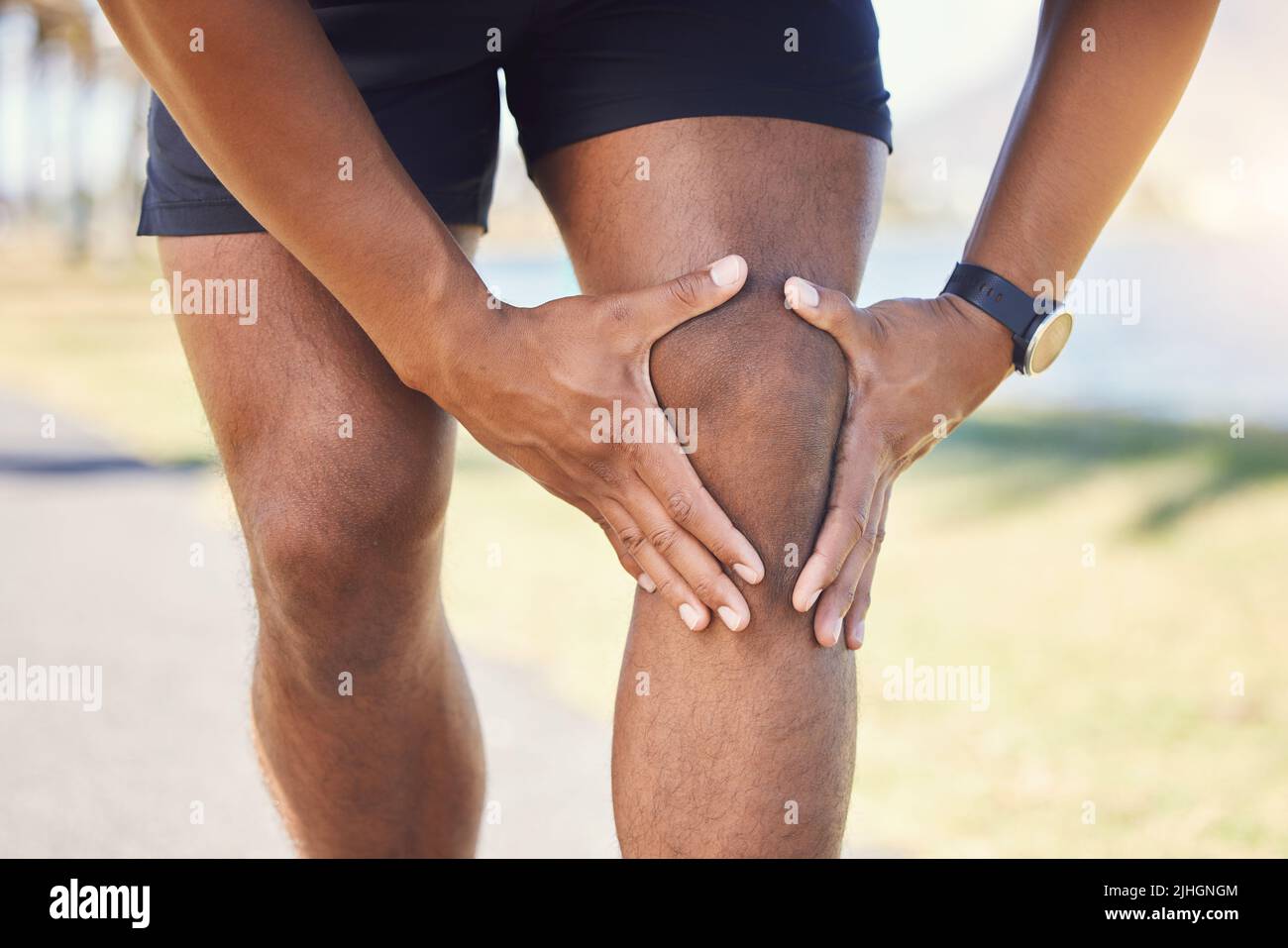 Closeup of unknown fit active mixed race man holding his knee in pain ...