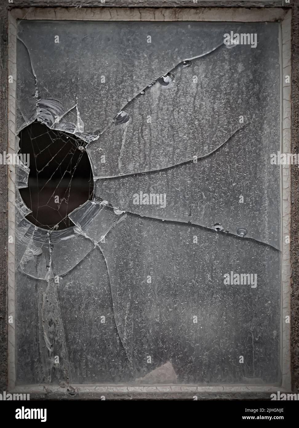 A vertical closeup of a broken glass window in an abandoned factory ...