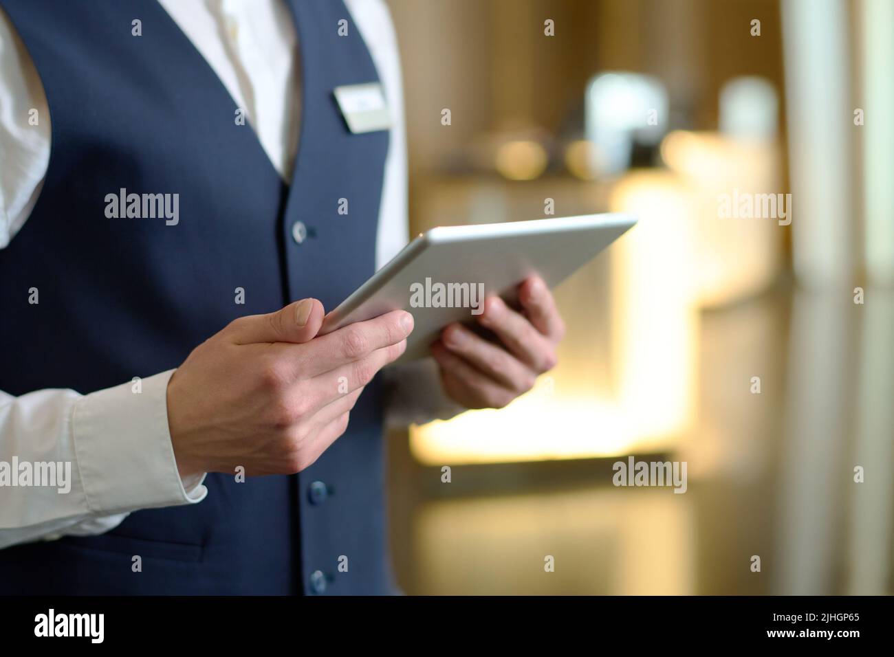 Digital tablet in hands of young male receptionist of luxurious modern ...