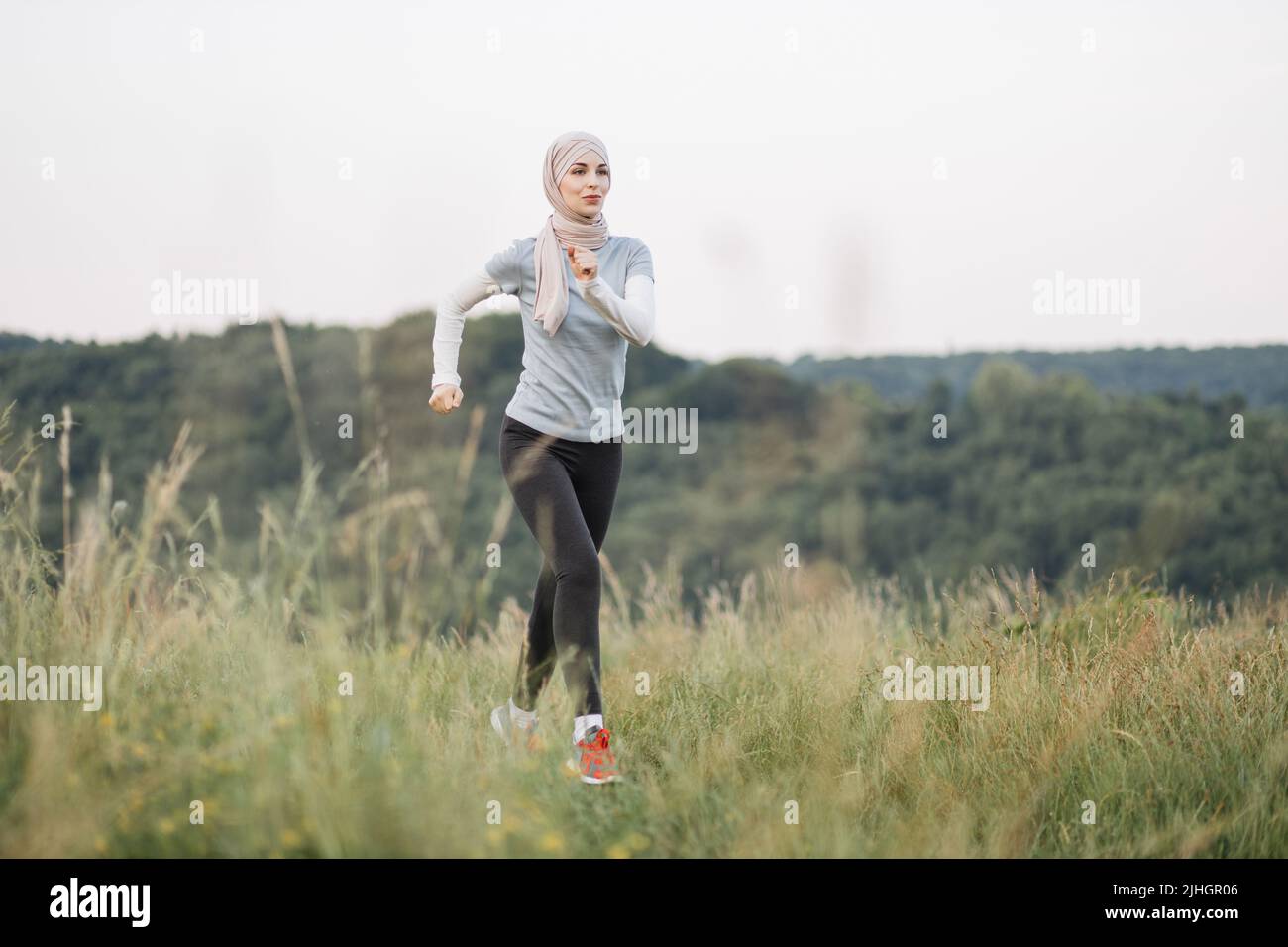 Happy arabian woman in hijab in activewear running at summer park ...