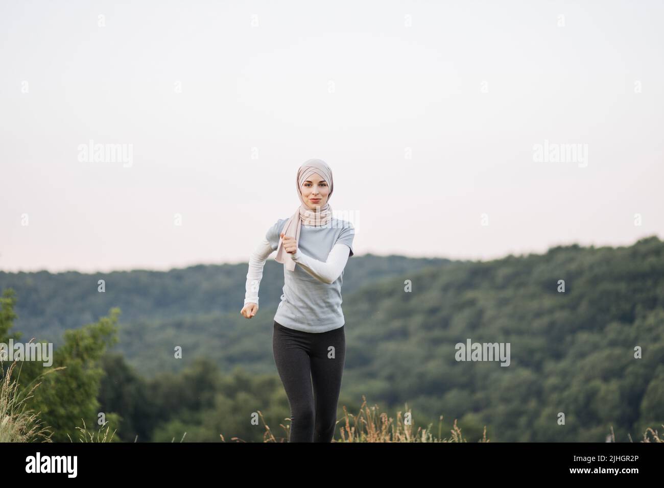 Jogging Arabic woman in hijab running in green park on beautiful summer ...