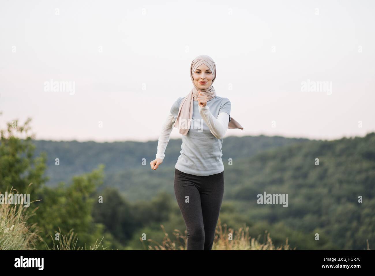 Jogging Arabic woman in hijab running in green park on beautiful summer ...