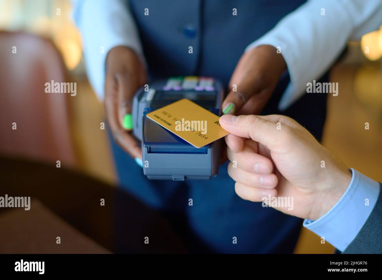 Young black woman in uniform holding payment terminal while businessman ...