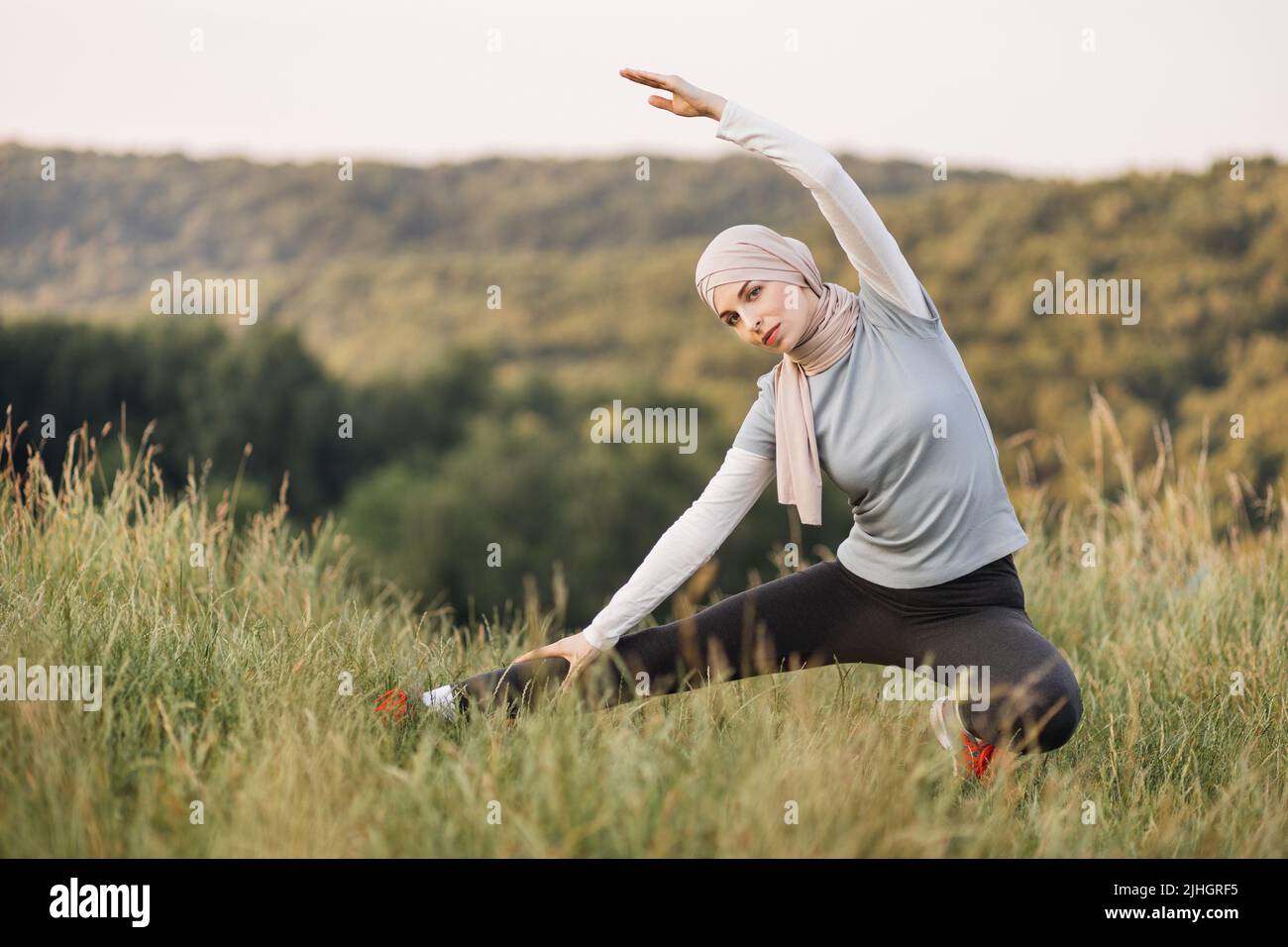 Outdoor sports concept. Athletic young Muslim woman in sportswear doing ...