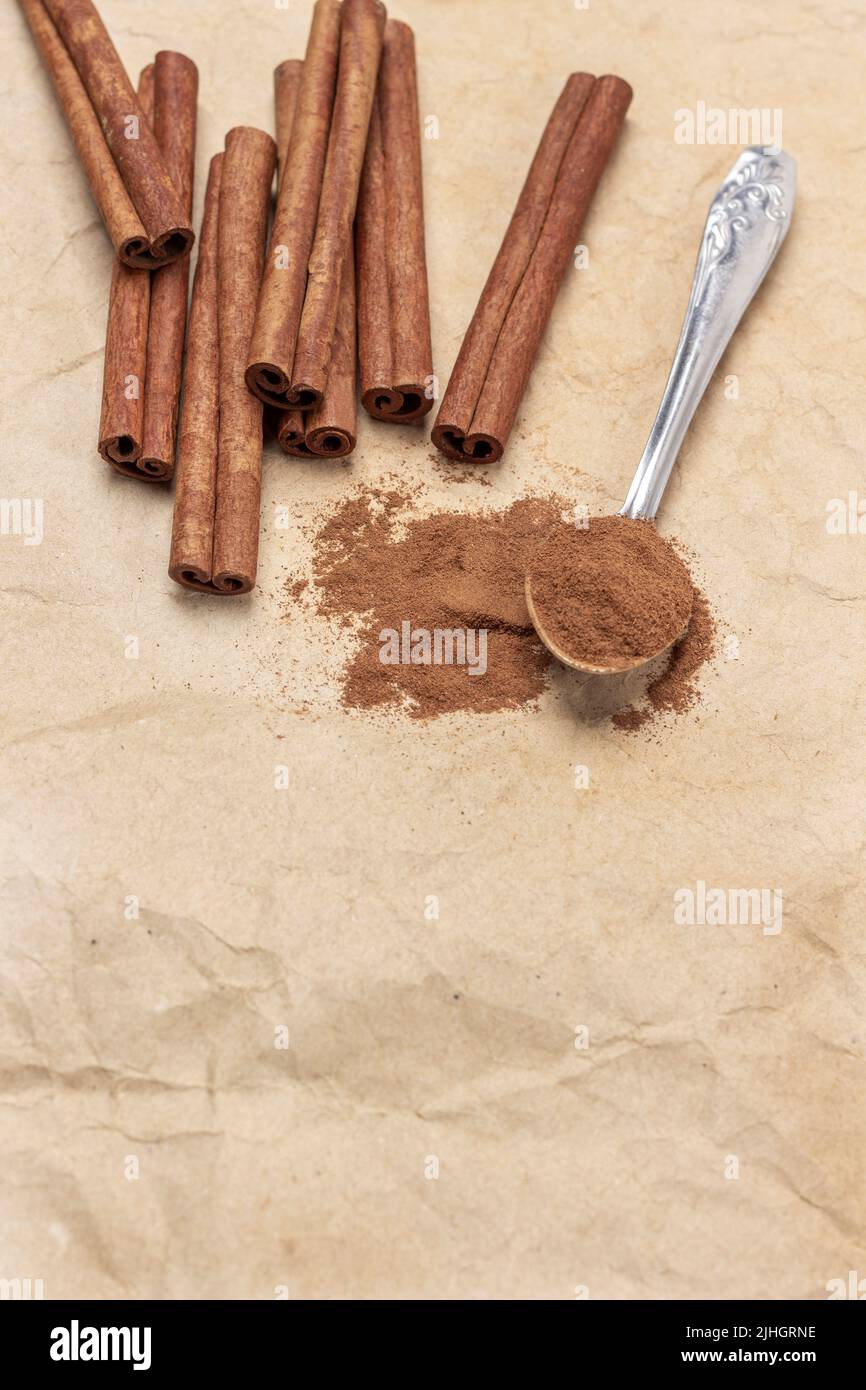 Ground cinnamon in metal spoon. Cinnamon sticks. Copy space. Top view ...