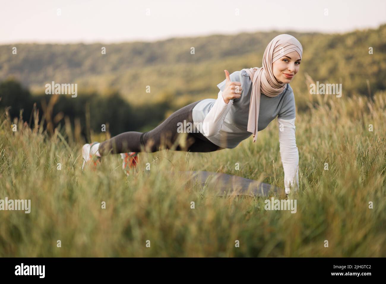 Portrait of attractive young Muslim woman smiling and doing plank ...