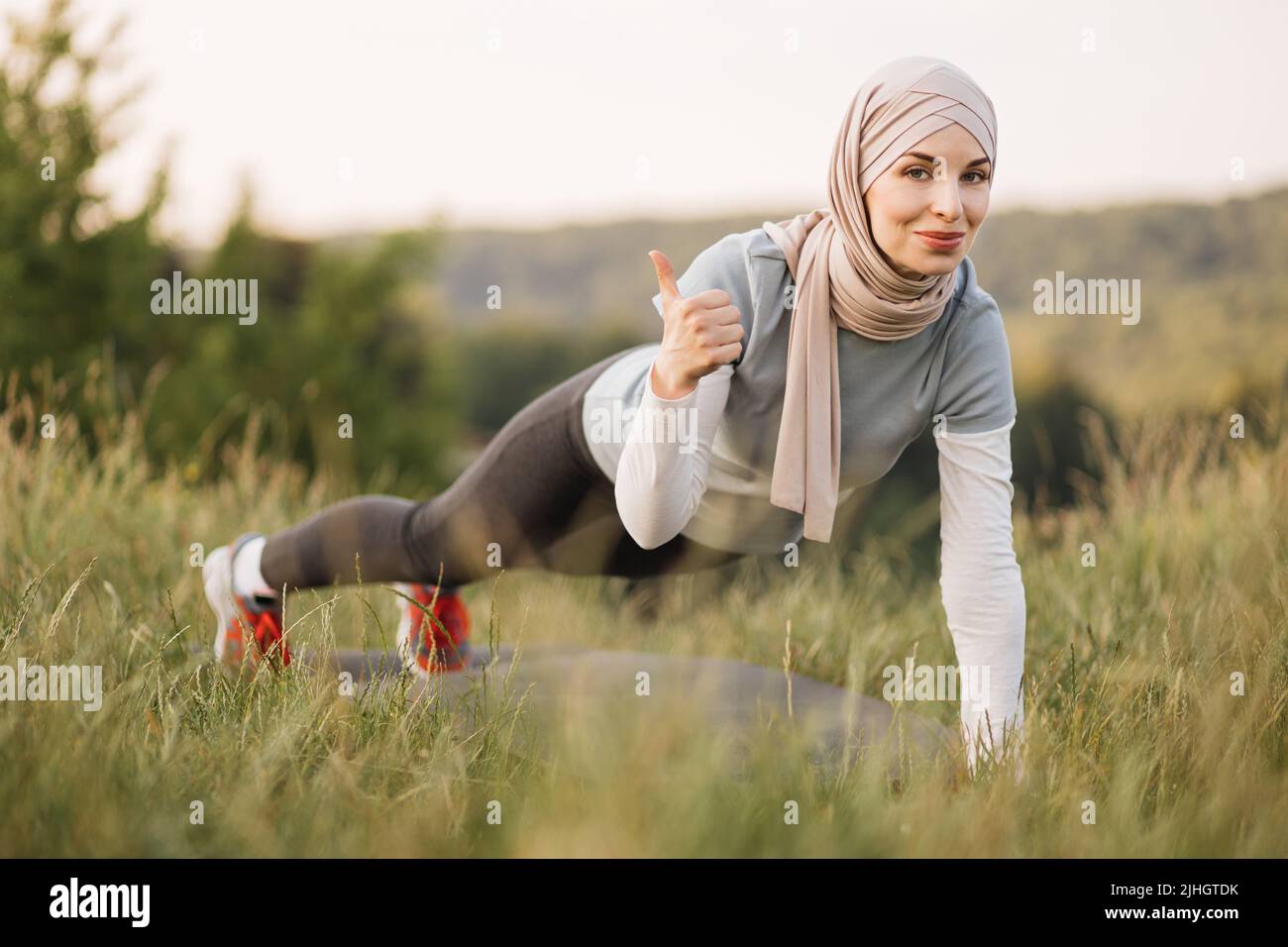 Portrait of attractive young Muslim woman smiling and doing plank ...
