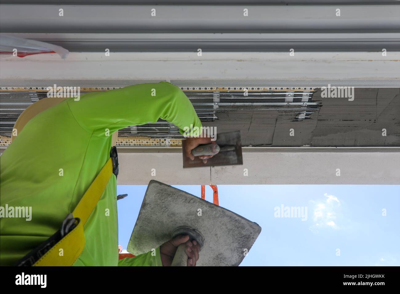 Construction worker on a harness, applying stucco mud to the soffit ...
