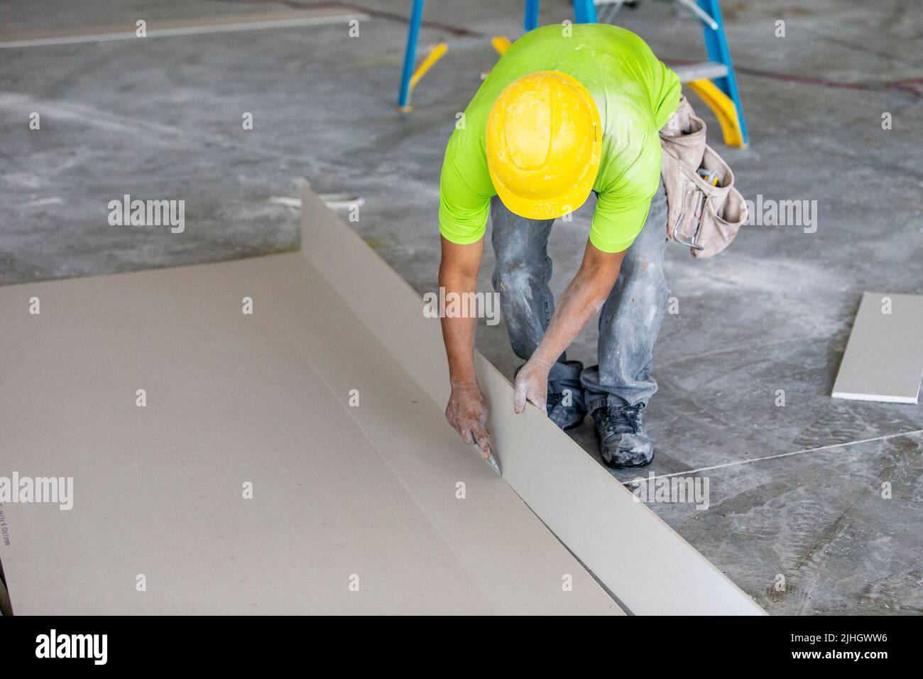 construction worker / drywaller is cutting a sheet of drywall for ...