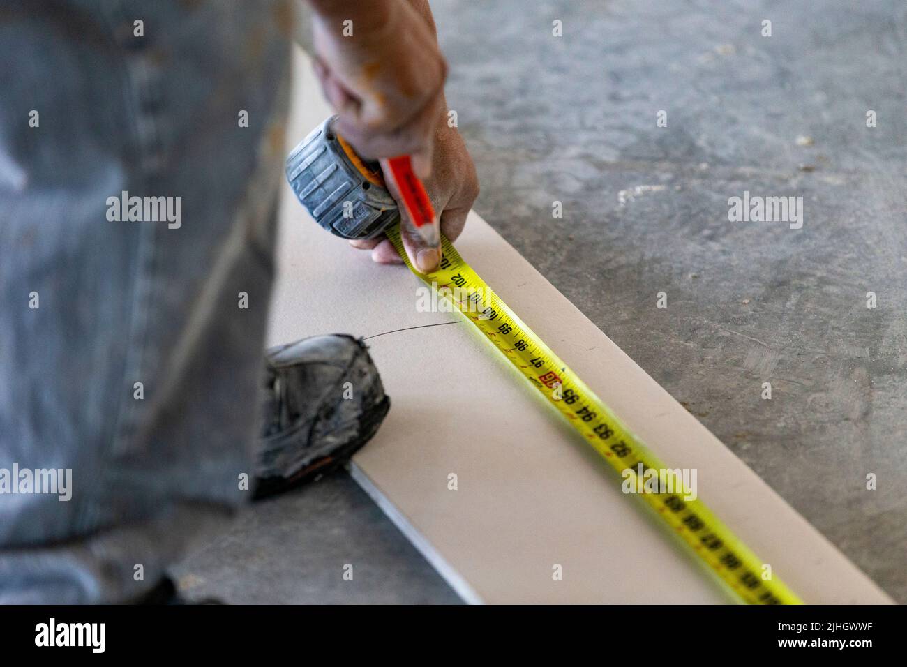 Qualified construction worker is measuring a piece of drywall for ...
