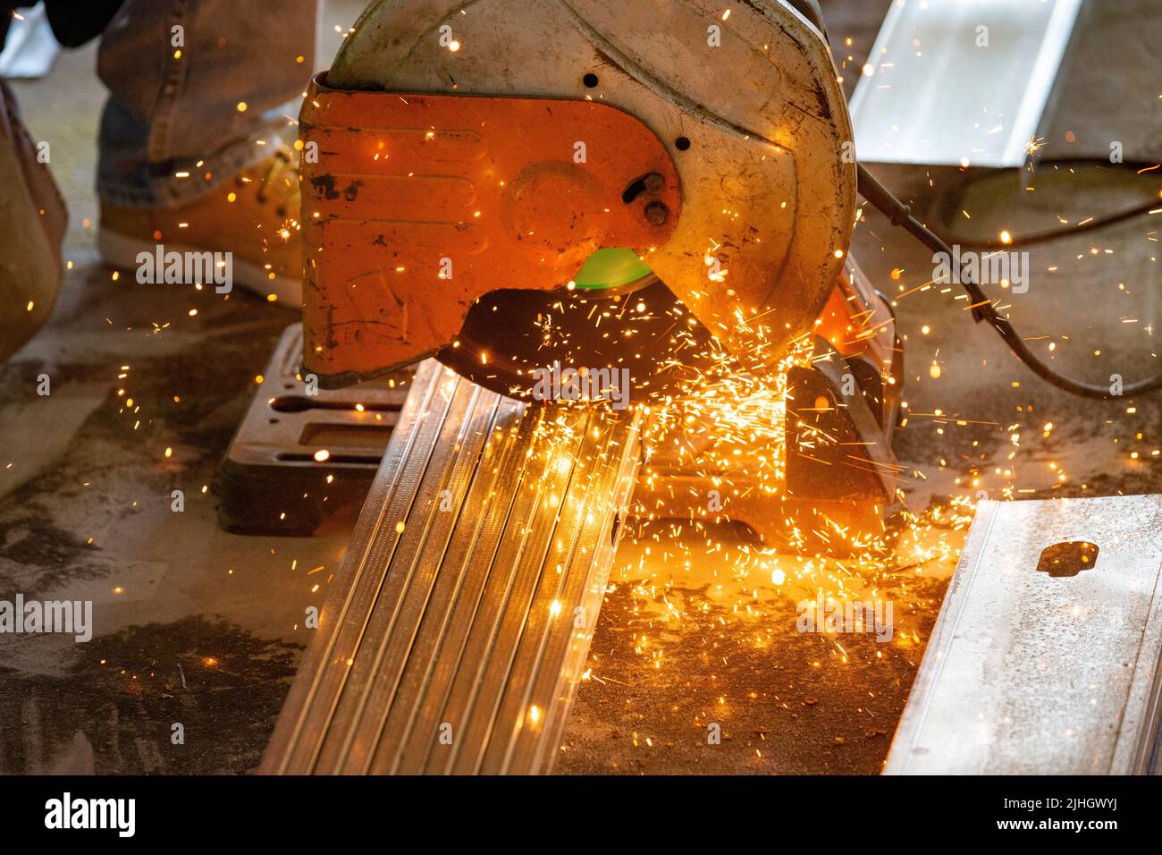 construction worker is using a metal power saw to cut galvanized steel ...
