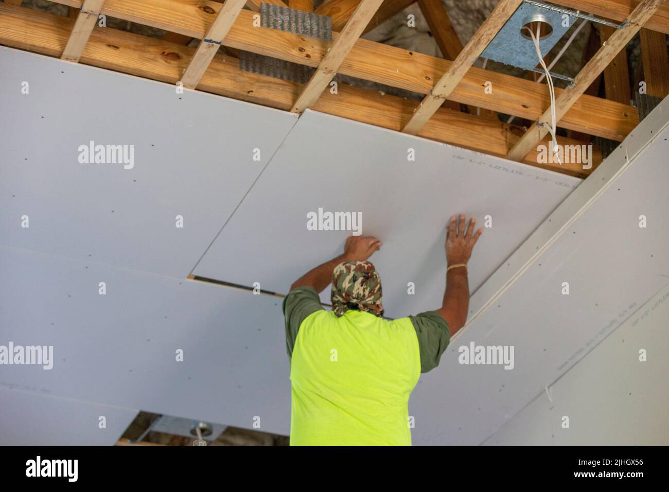 Skilled construction drywaller is installing a custom cut drywall panel ...