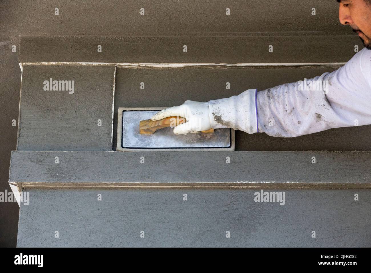 Skilled construction worker using a wet sponge to clean off any stucco ...