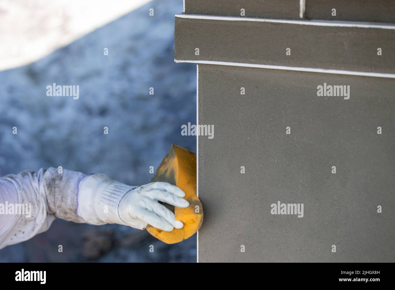 Skilled construction worker using a wet sponge to clean off any stucco ...