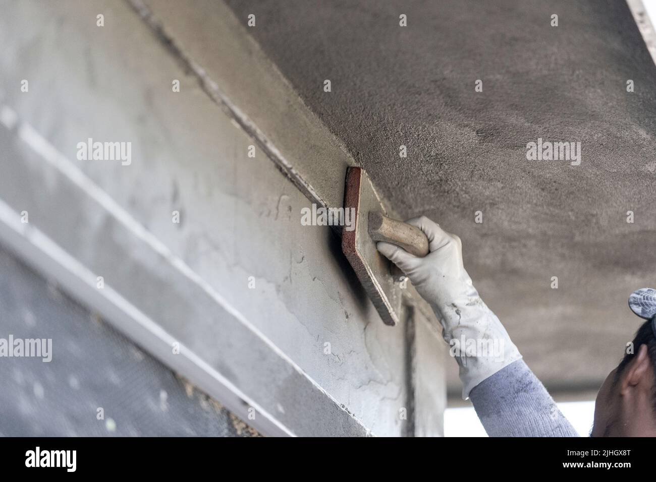 Skilled construction worker is using a wet sponge trowel to smoothen ...