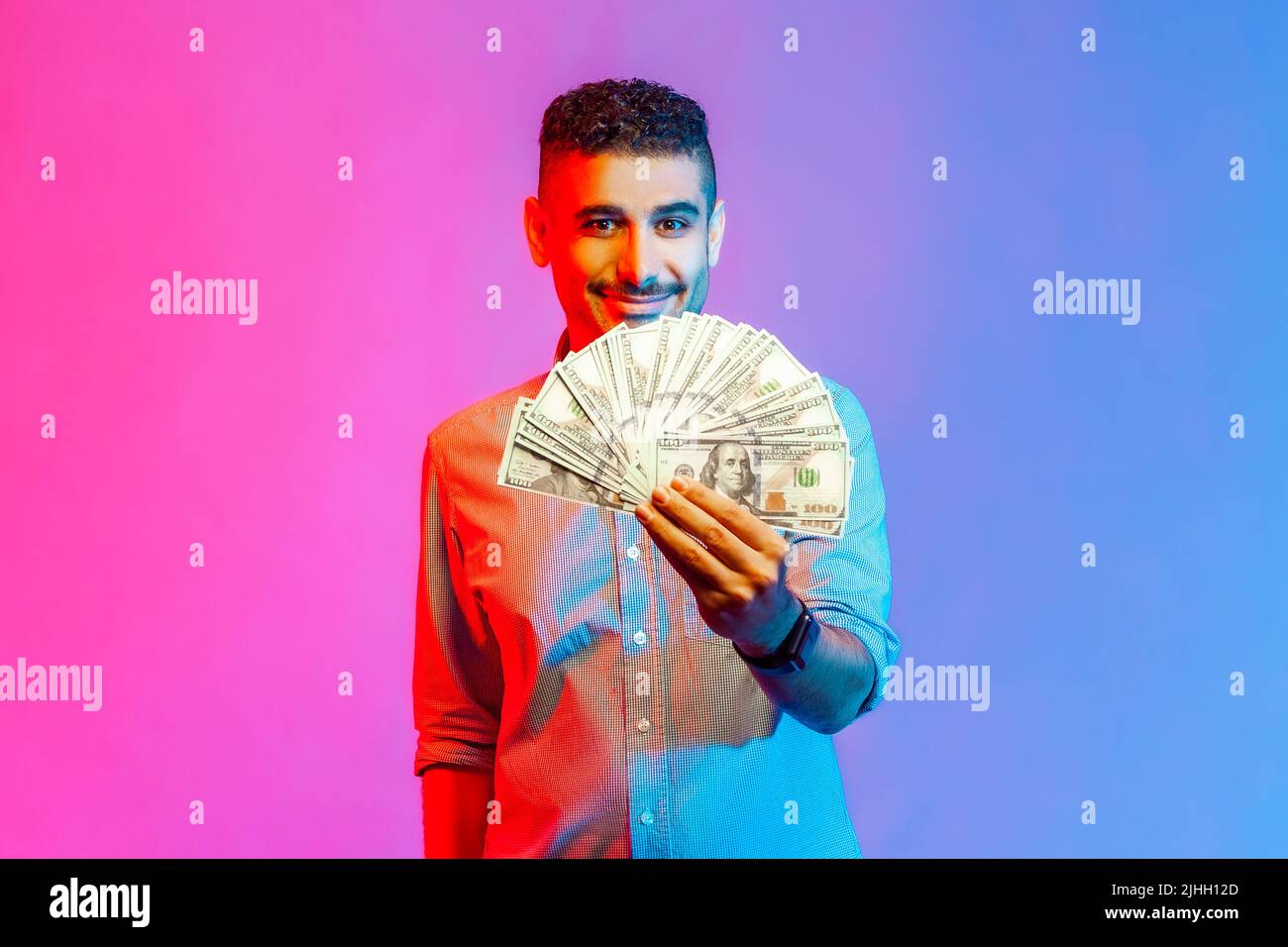 Portrait of rich handsome man in shirt holding dollars, looking at ...